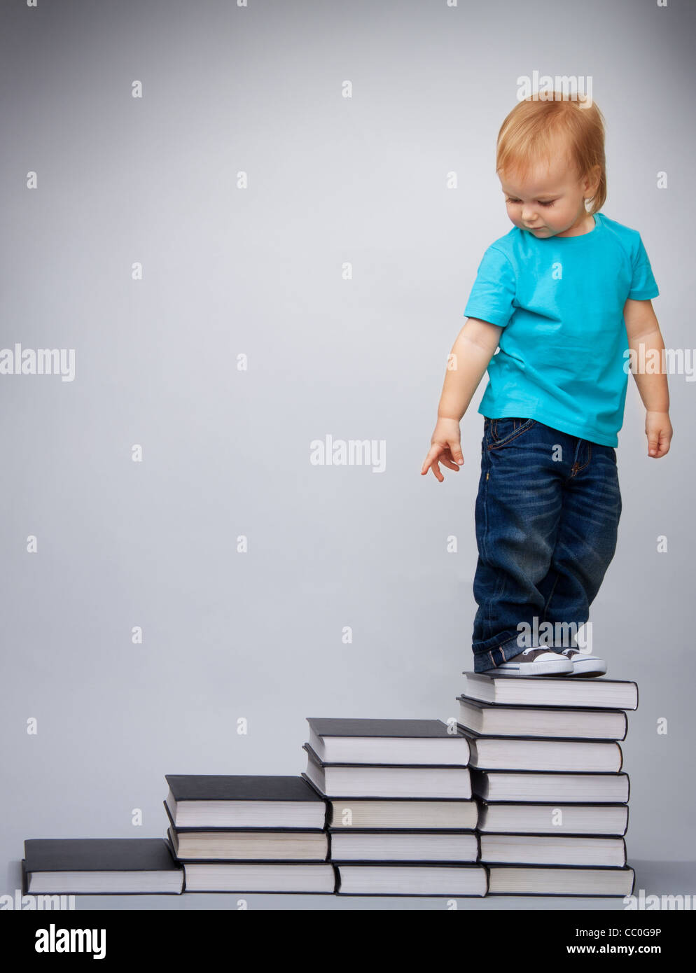 Kid on top of early education leader made of pile of books standing and ...
