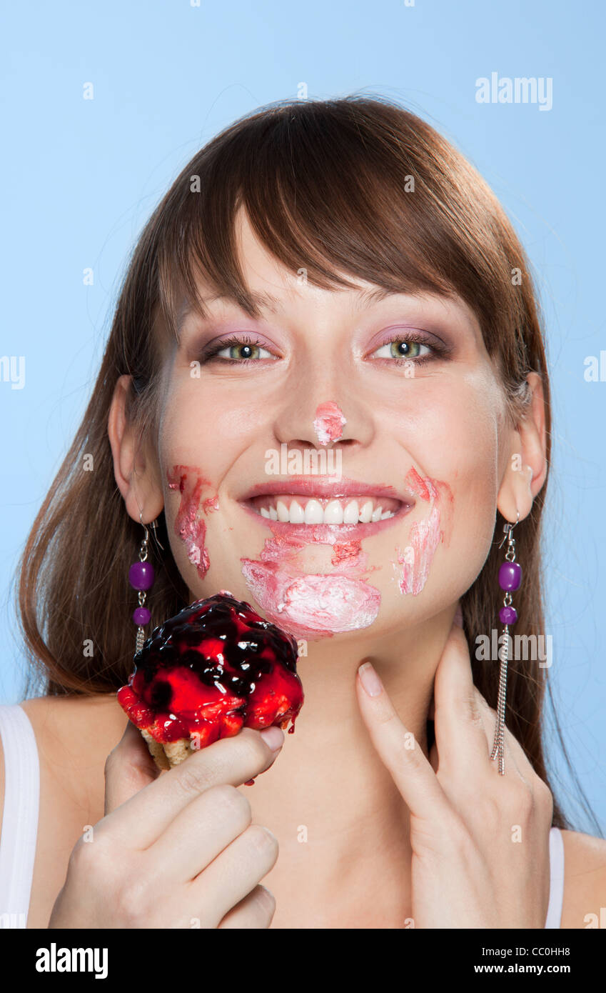 Happy girl with her face smear in cake smiling and looking at camera ...