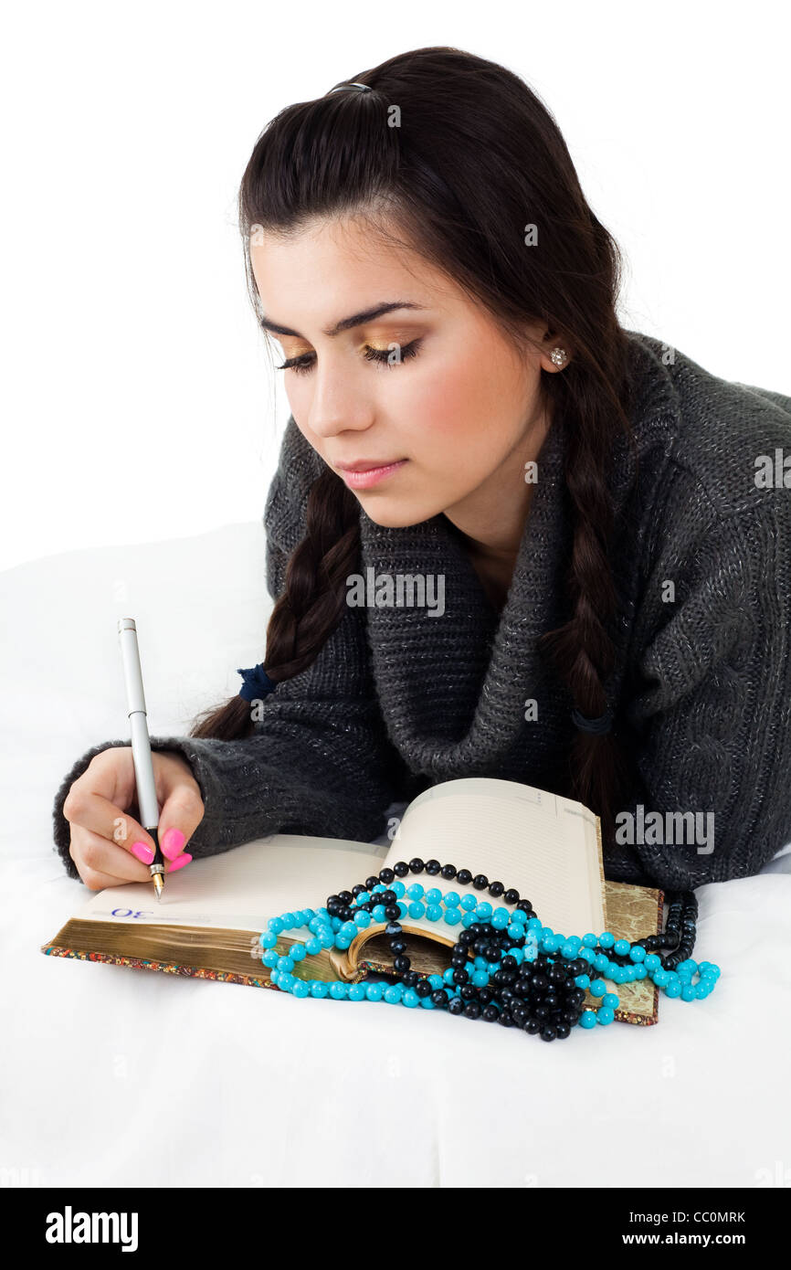 Positive young woman lay in bed and write down into dairy Stock Photo ...