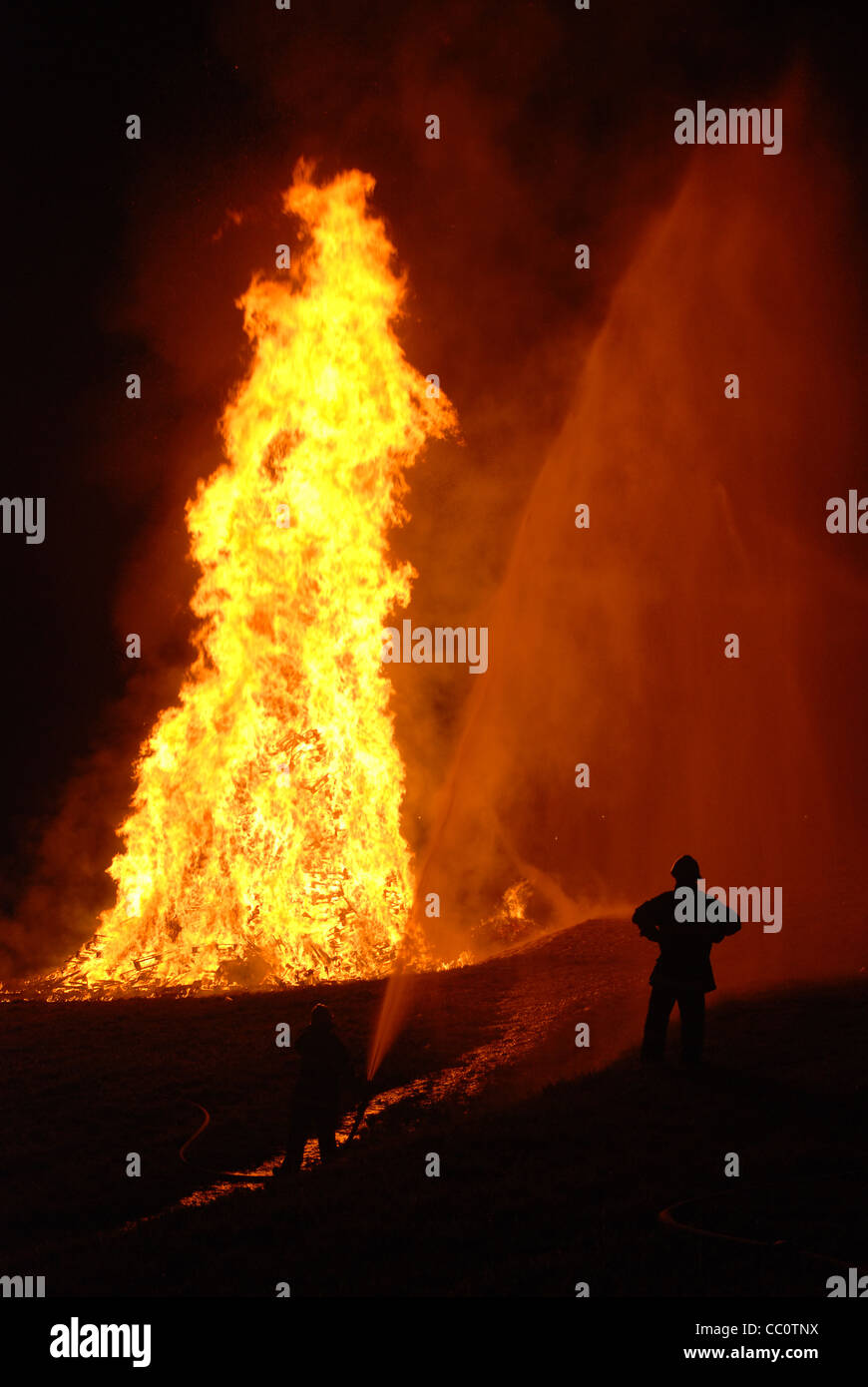 Two firemen working to extinguish a huge fire Stock Photo - Alamy