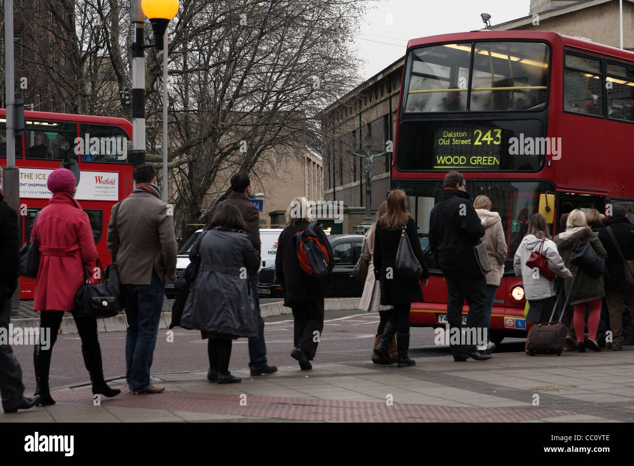 a queue of people waiting to board a red London bus Stock Photo - Alamy