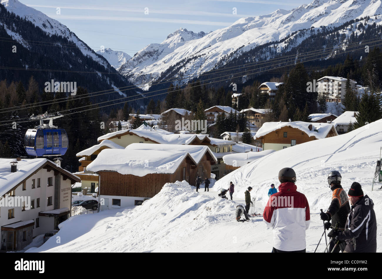 Winter scene with Galzig gondola cable car above village and skiers on ...