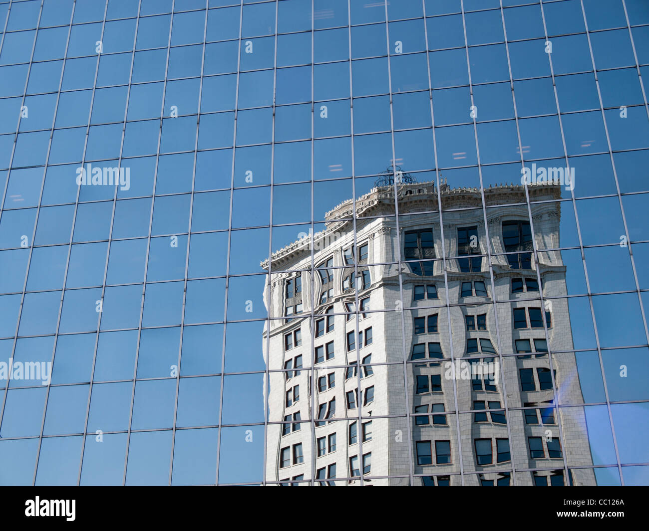 Old building reflects into the side of a modern mirrored glass paneled ...