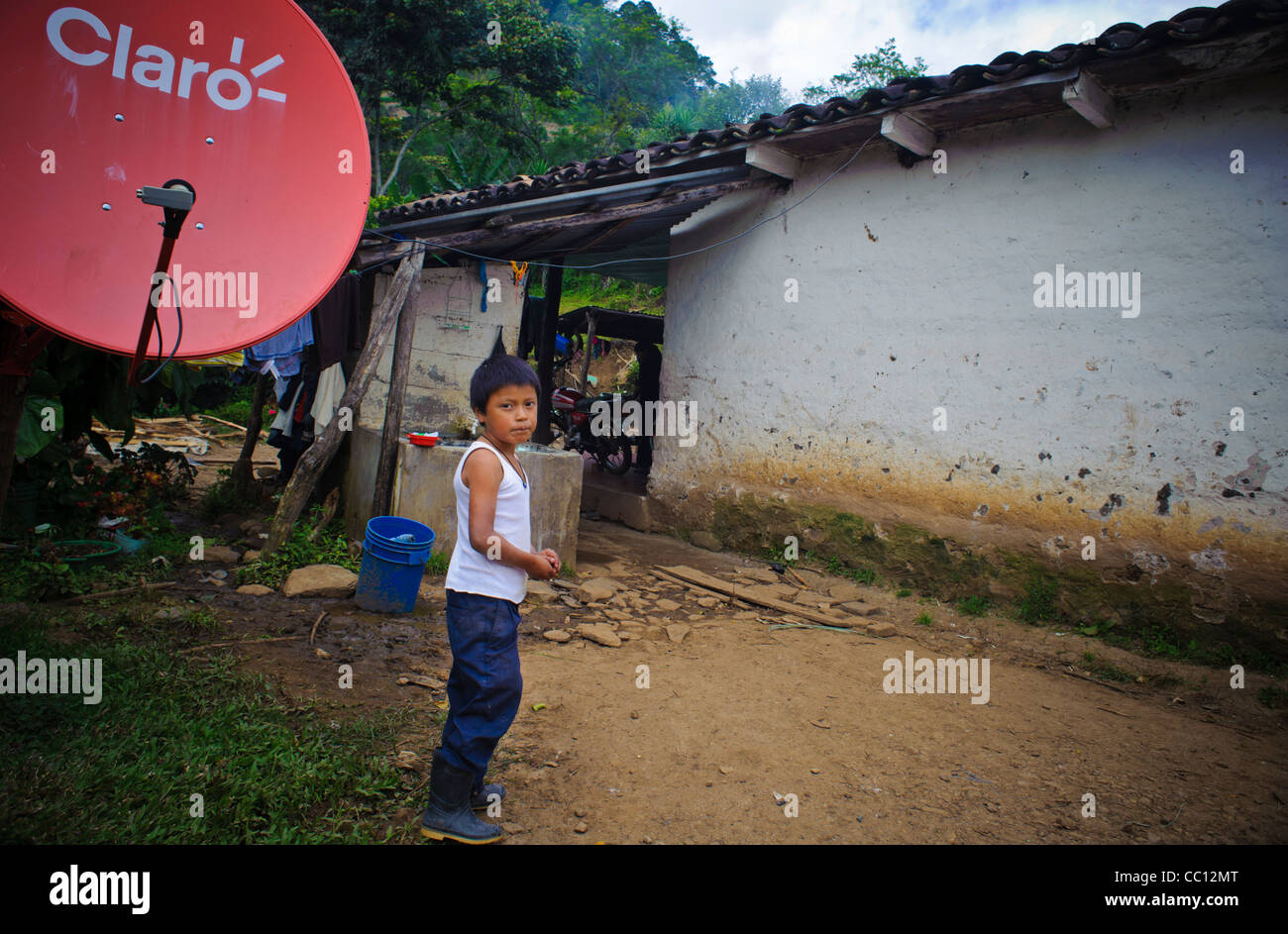 Young boy at his poor rural house with digital mobile network dish ...