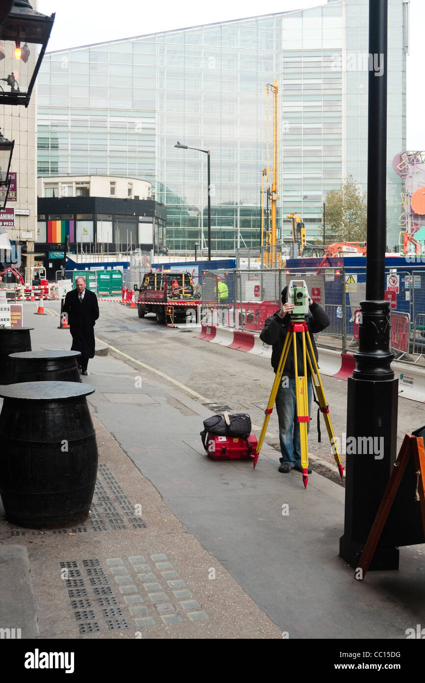 A surveyor using an auto levelling tool surveys an area outside a ...