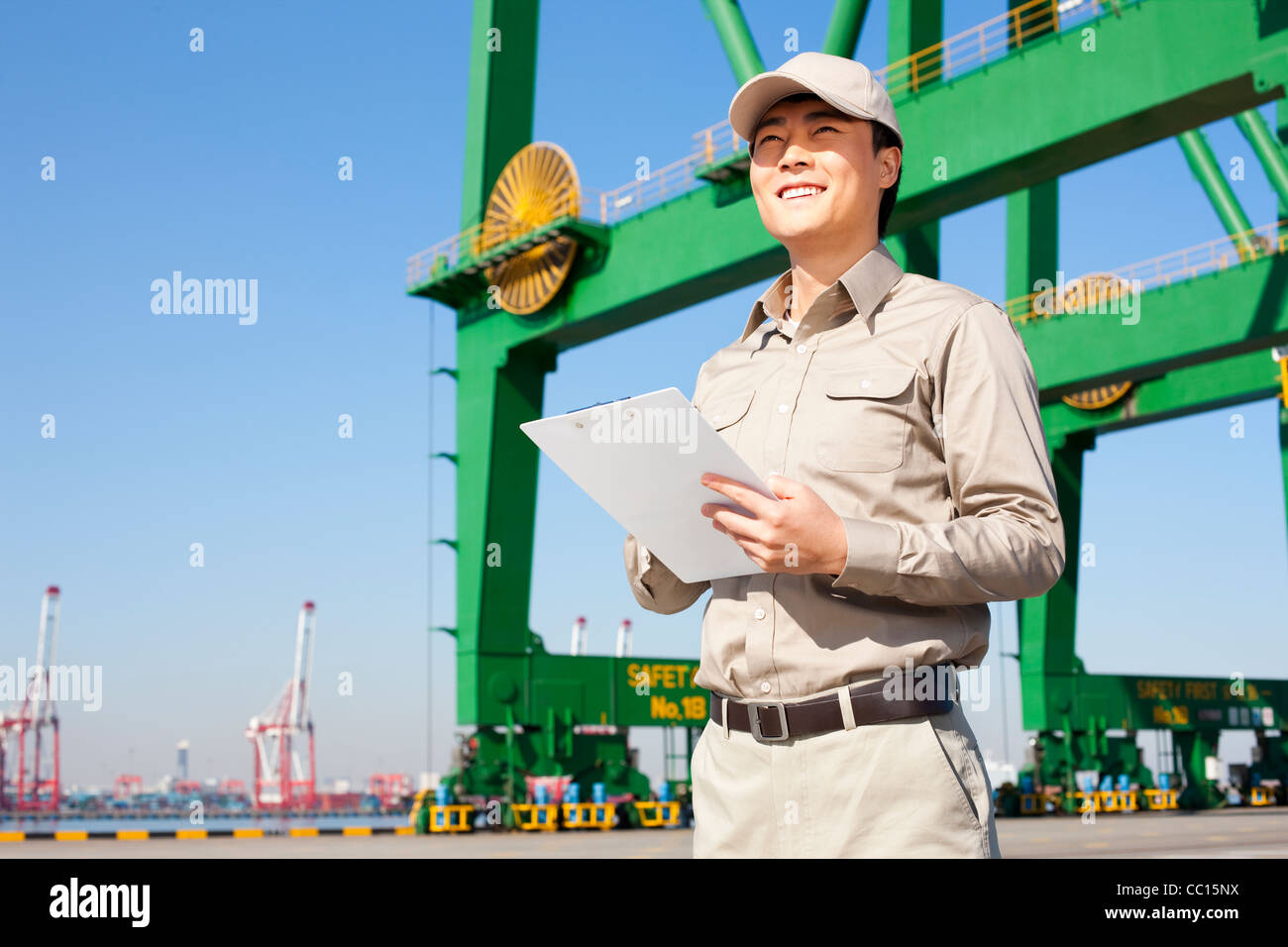 Male shipping industry worker with shipping dock and crane in the ...