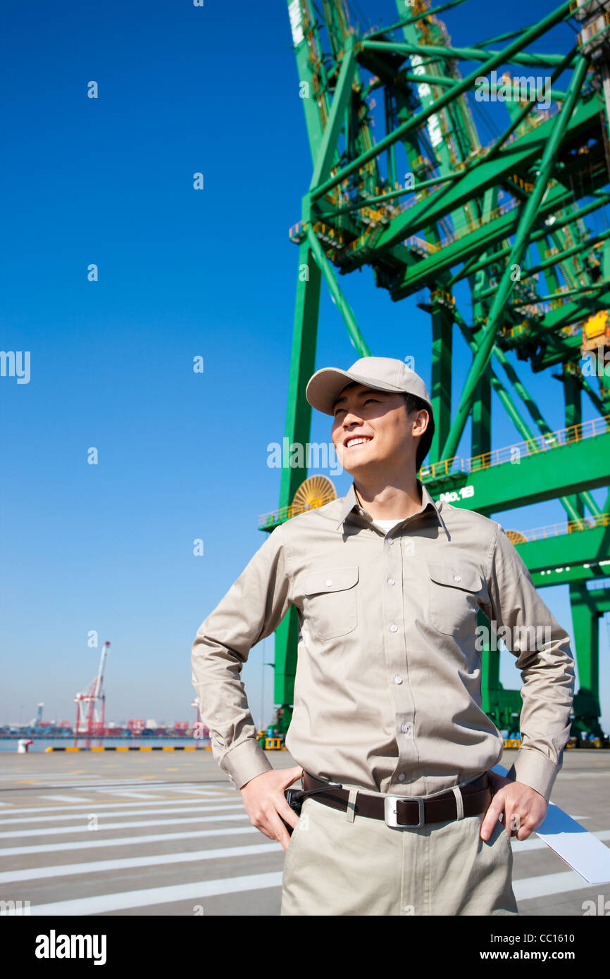 Male shipping industry worker with hands on hips with shipping dock ...
