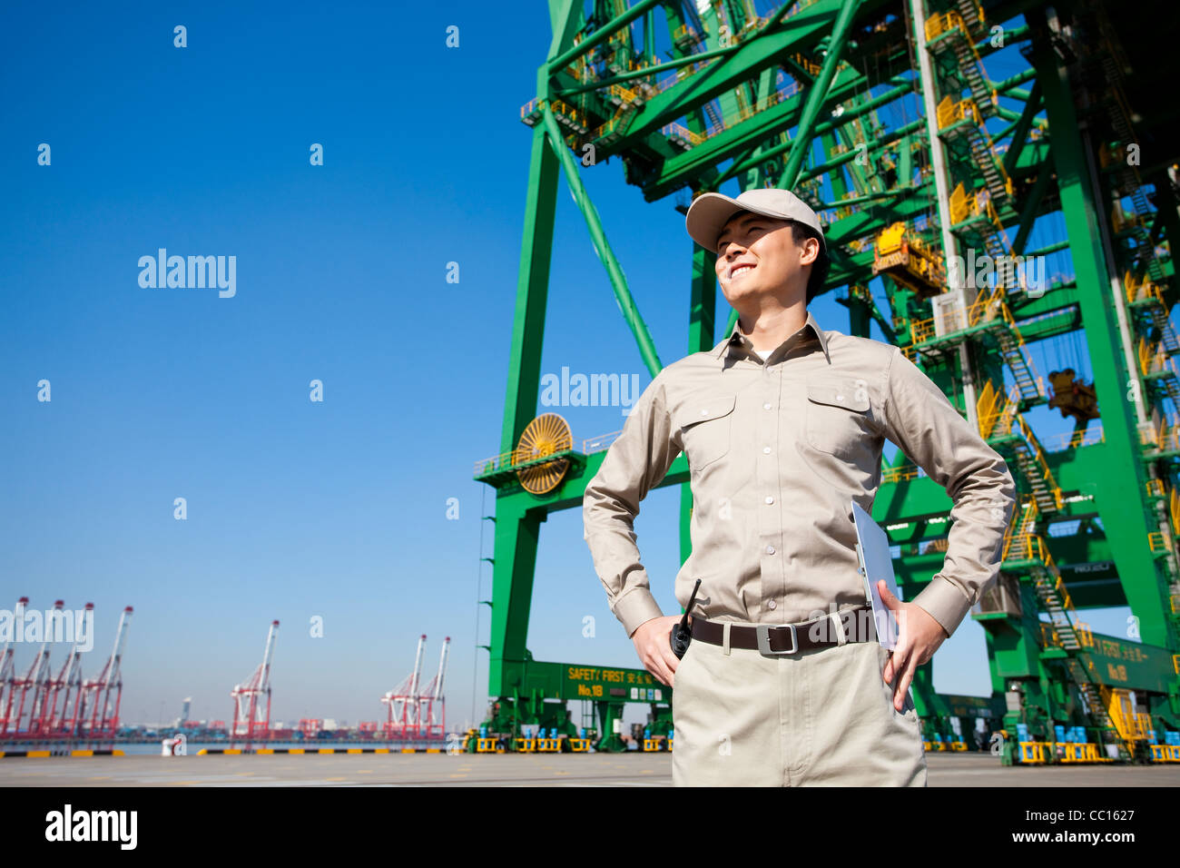 Male shipping industry worker with hands on hips with shipping dock ...