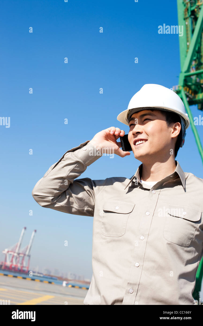 Male shipping industry worker on the phone with shipping dock ...
