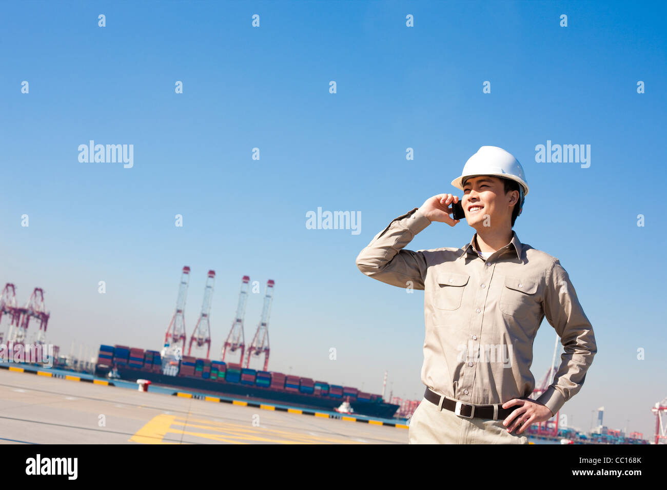 Male shipping industry worker on the phone with shipping dock ...