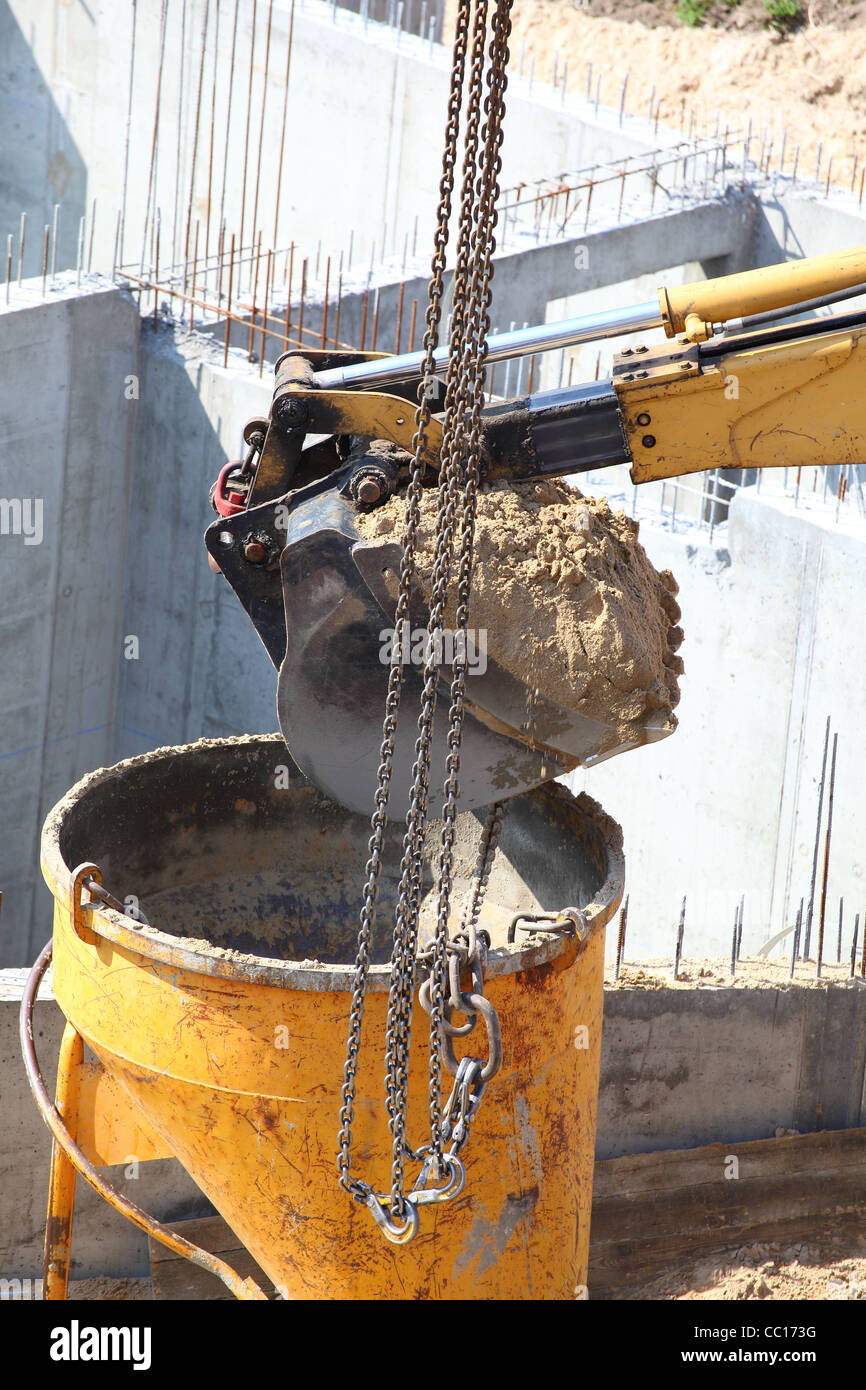 digger, excavator construction building site pouring concrete in form ...