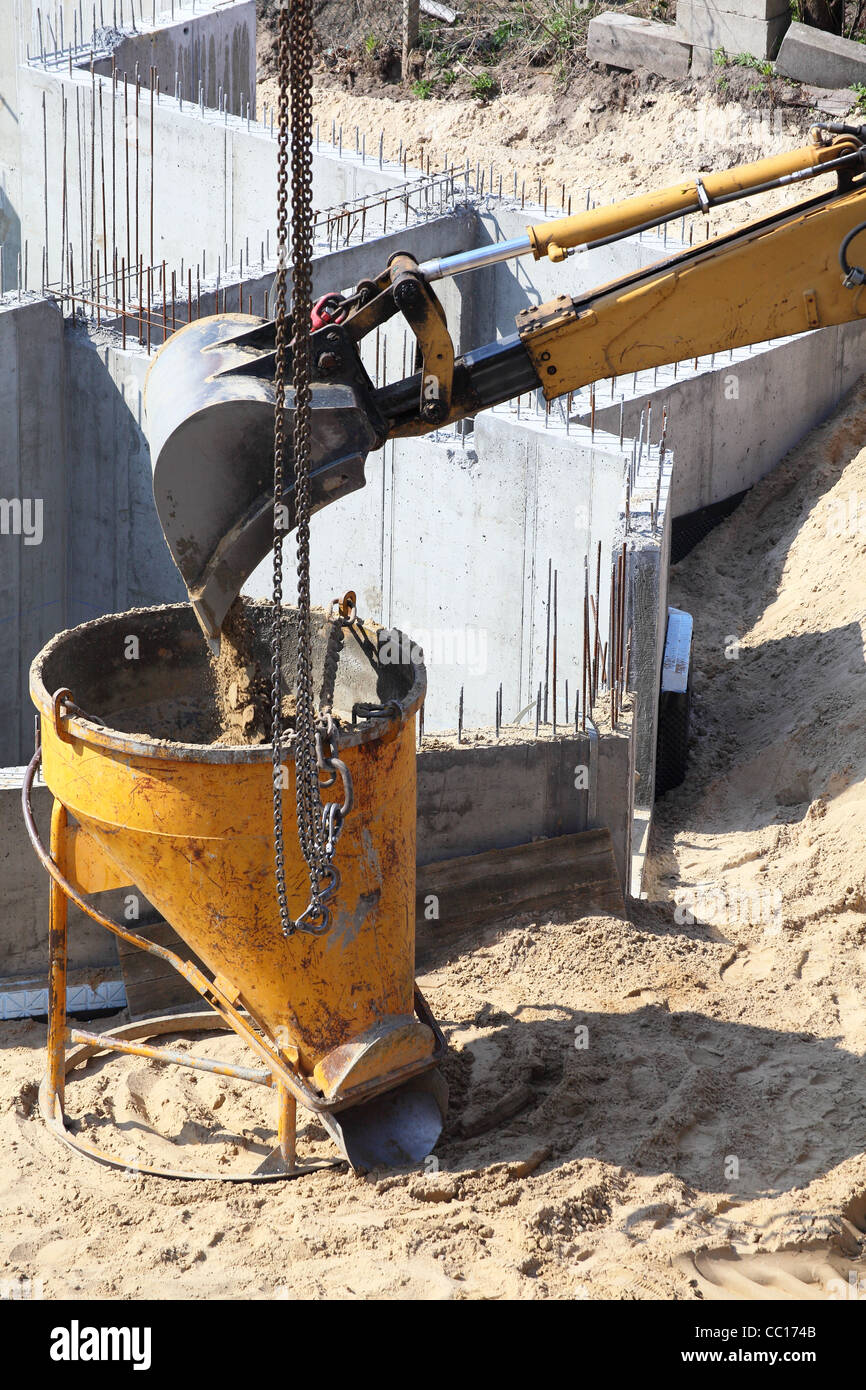 digger, excavator construction building site pouring concrete in form ...