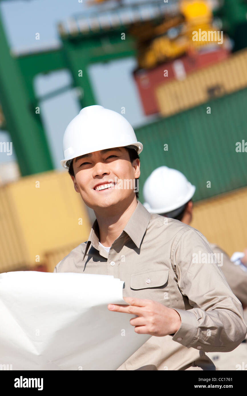 Male shipping worker checking blueprints Stock Photo - Alamy