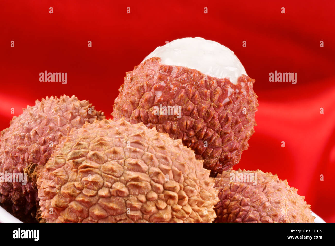 Close-up of some litchis (lychee) over a red background Stock Photo - Alamy