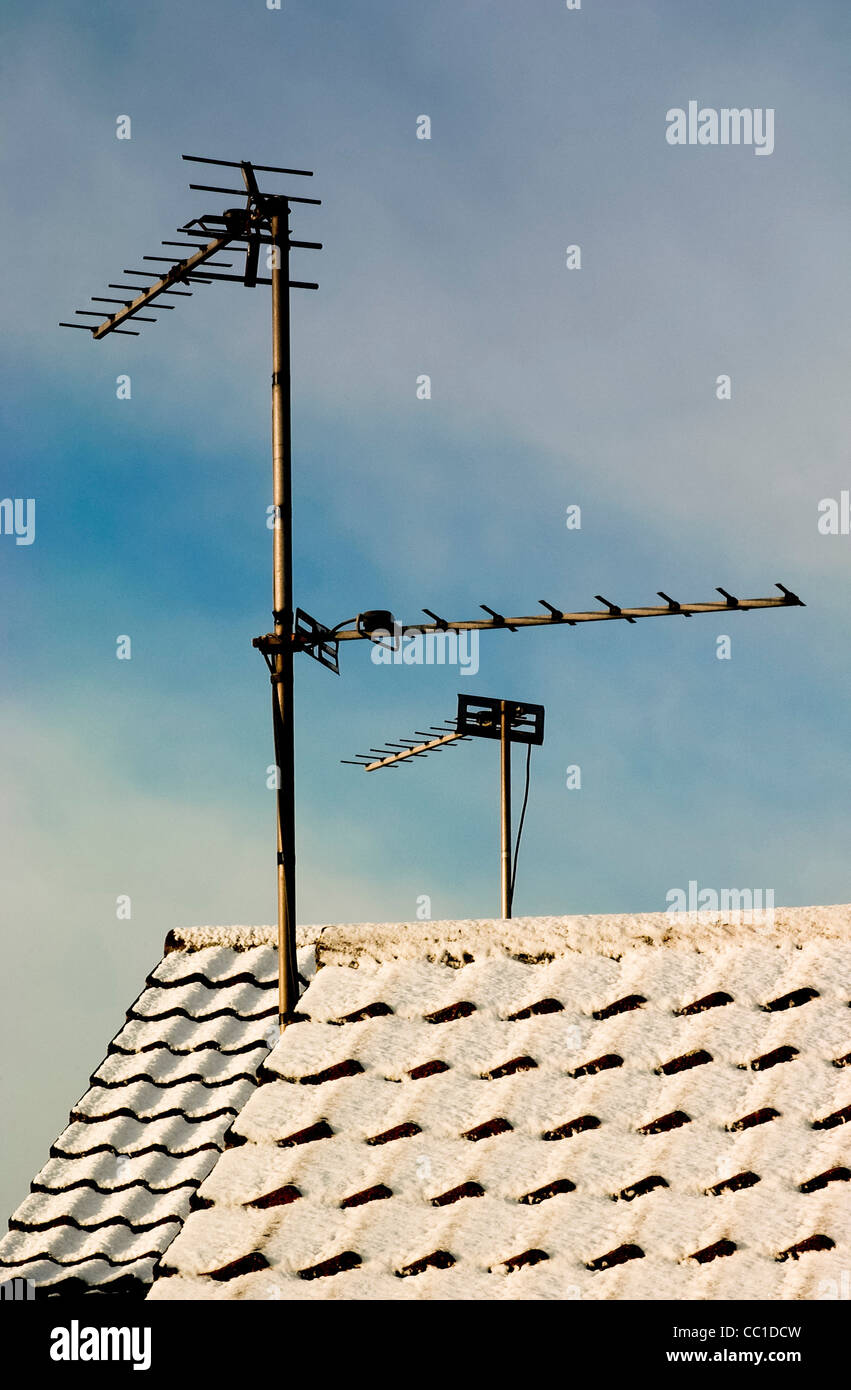 Snow covered tiled roofs with TV aerials against a blue sky Stock Photo ...