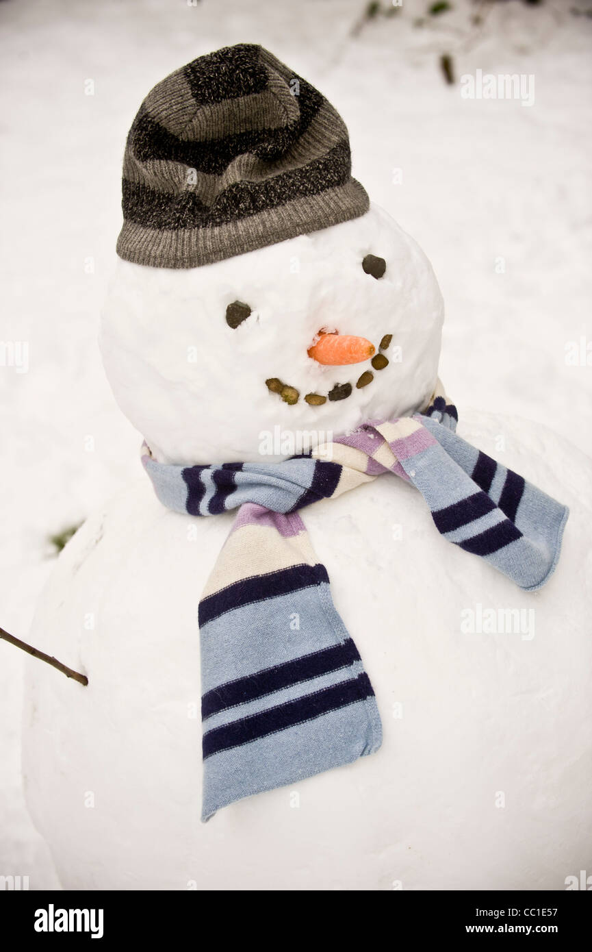 Snowman wearing a grey striped hat and a blue striped scarf in a UK ...