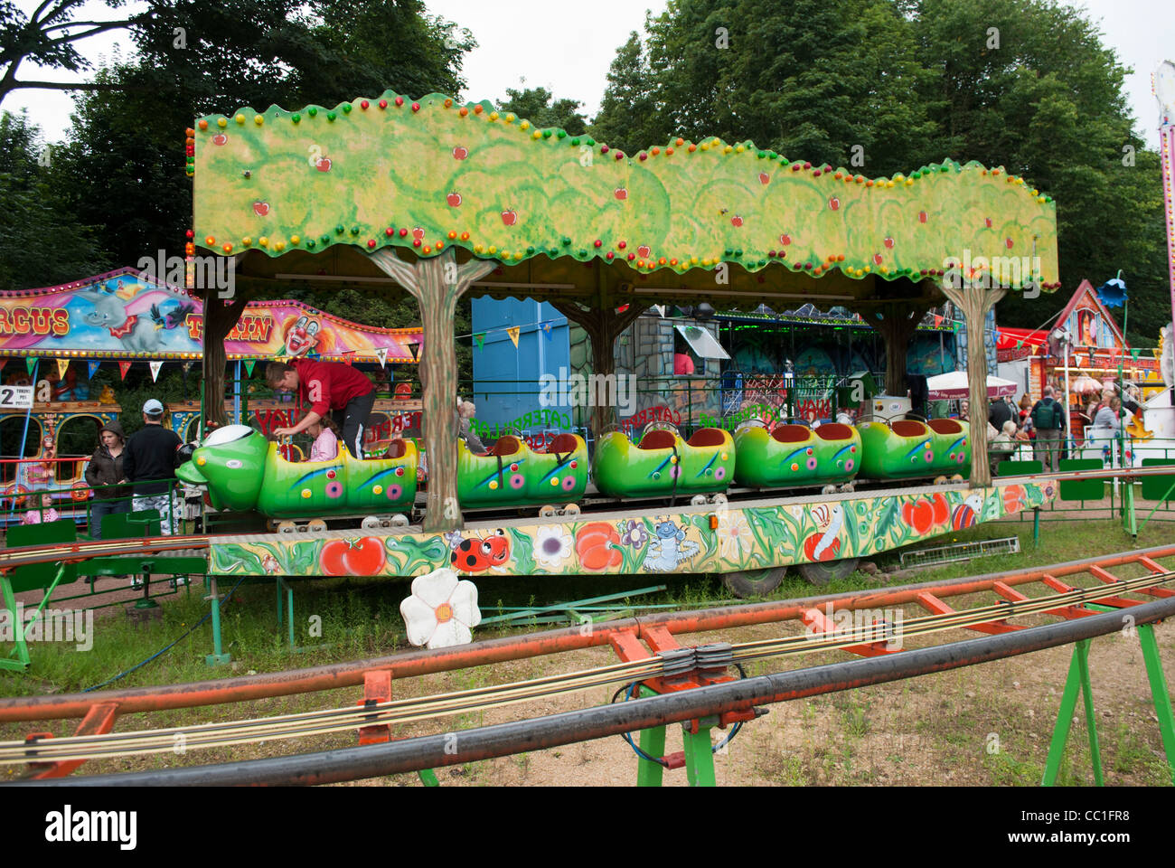 Child being seated on caterpillar / centipede fairground ride at Robin ...