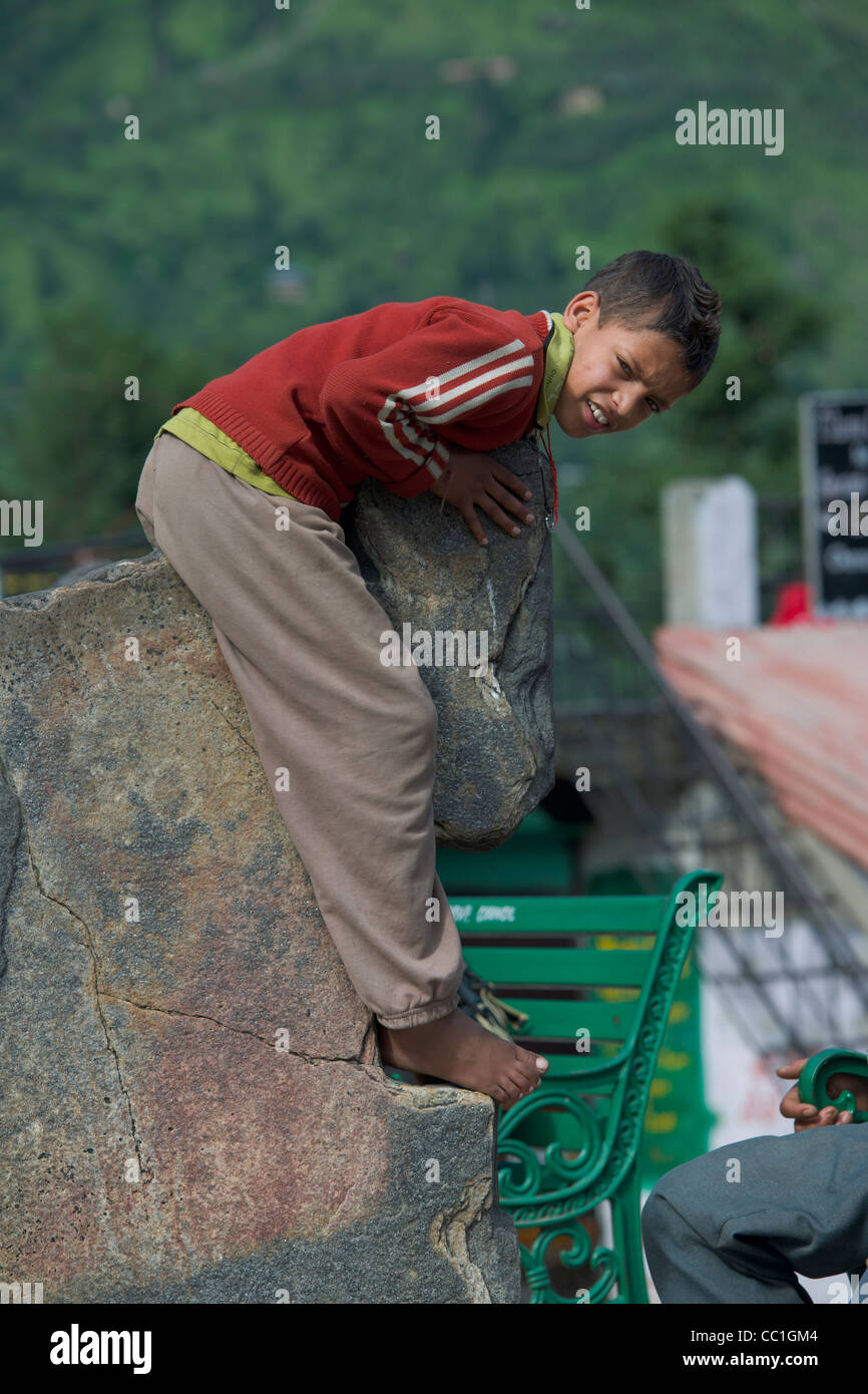 Boy playing on the rock statue outside the Manu Temple, Old Manali ...