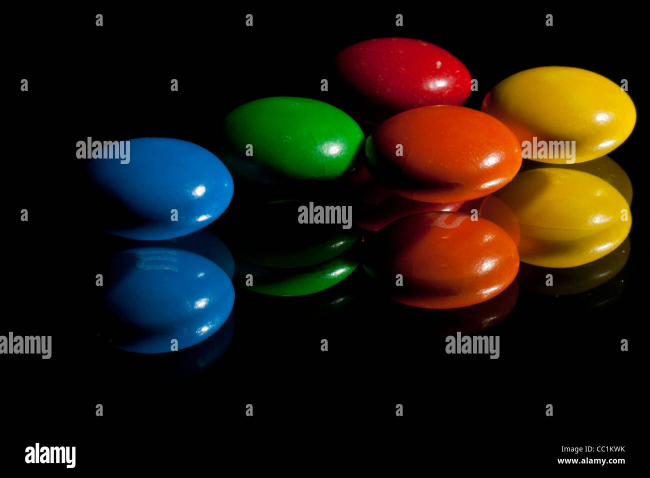 Coloured M&M sweets on a black background with reflections Stock Photo ...