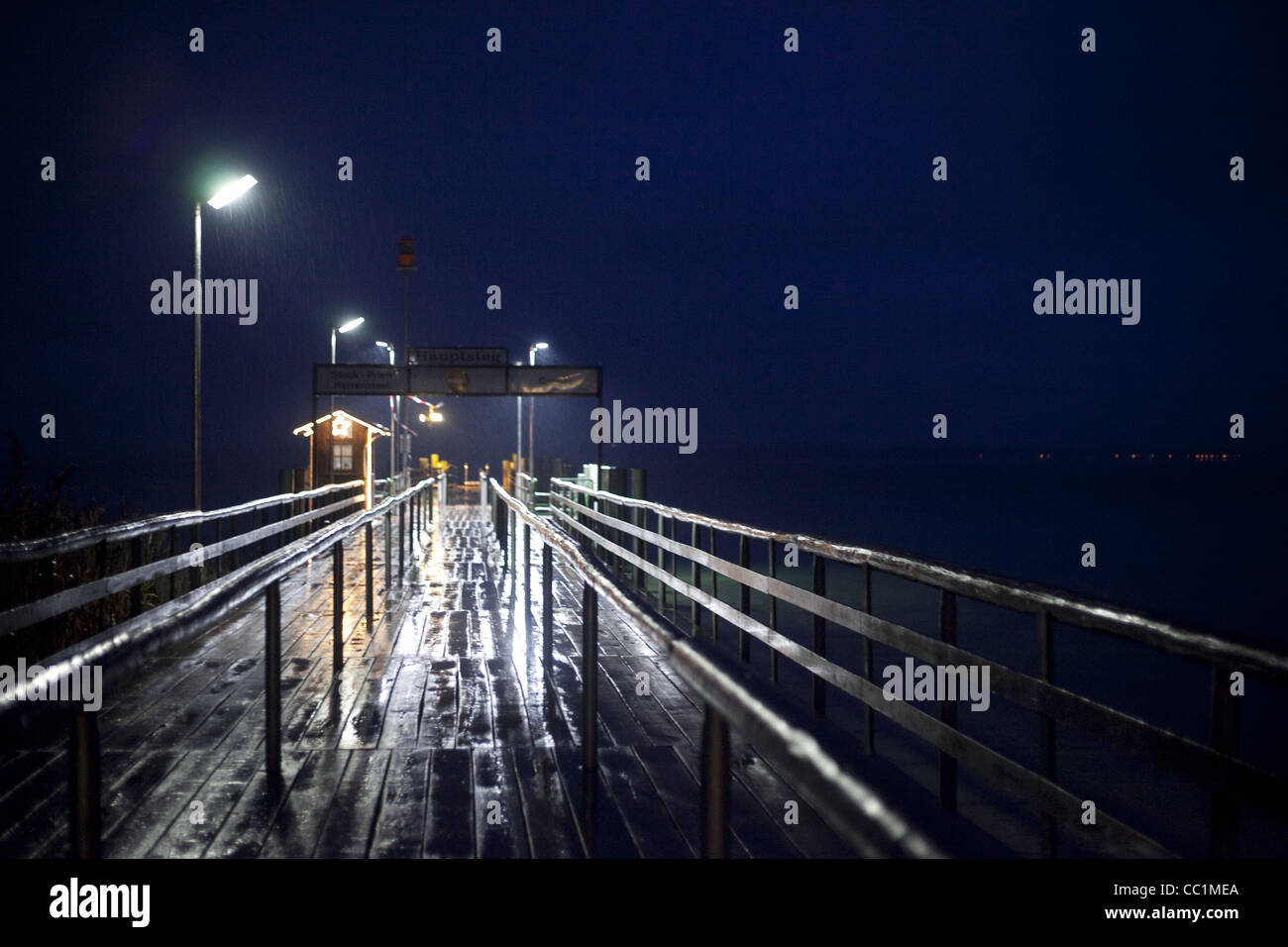 A street lamp lights a passenger ferry dock against a rainy evening ...