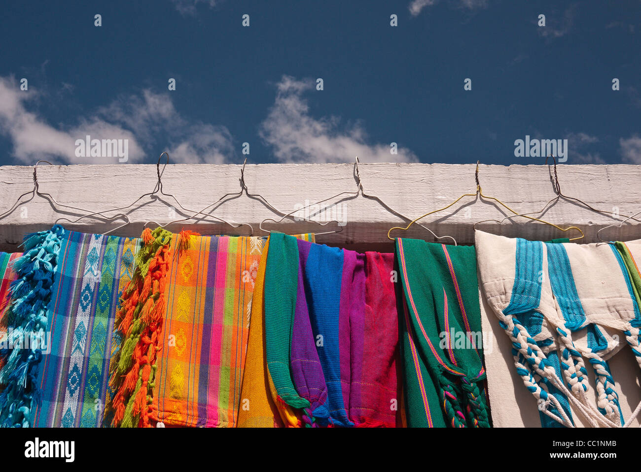 A variety of very colorful cloth weavings hang in a display at the ...