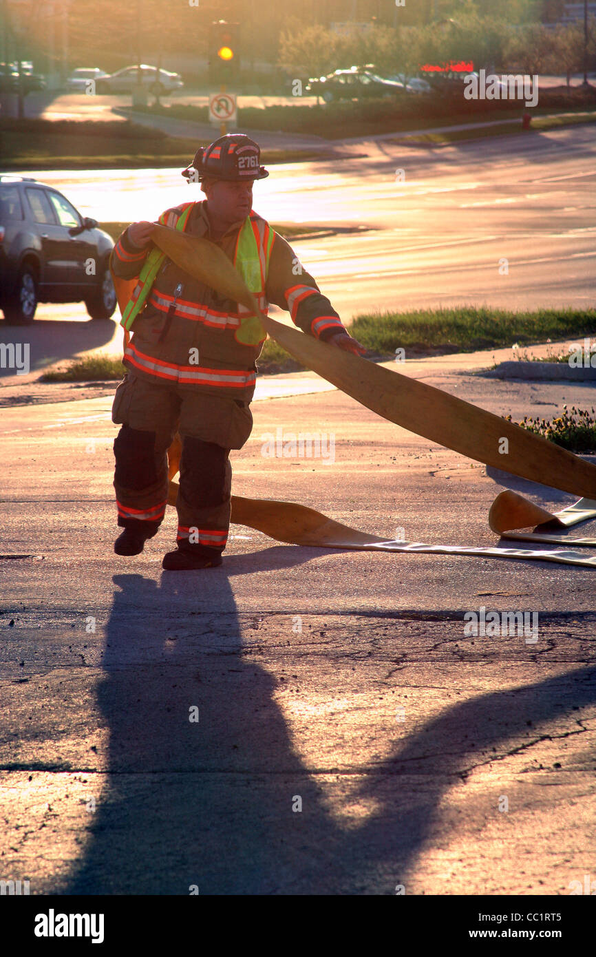 A firefighter pulling a hoseline at an emergency fire scene Stock Photo ...