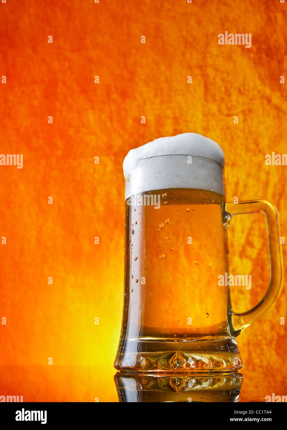 Glass of beer close-up with froth over orange background Stock Photo ...
