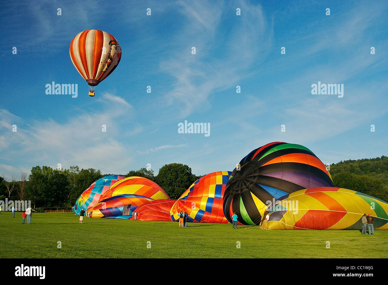 Balloons on the ground inflating and one balloon in flight in the ...
