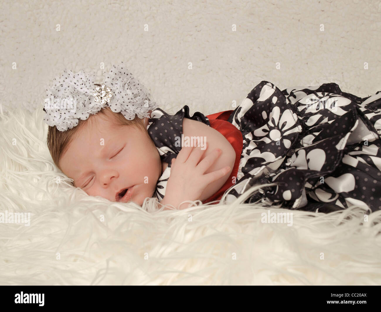 Newborn girl sleeping peacefully on a white fur rug Stock Photo - Alamy