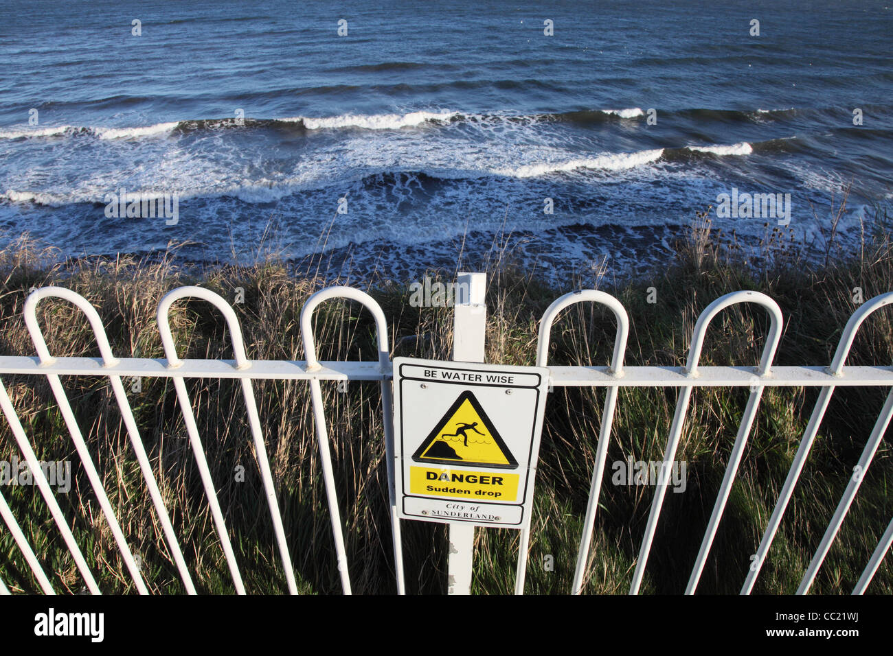 Sign or notice Danger Sudden Drop, be Water Wise, above cliffs Roker ...