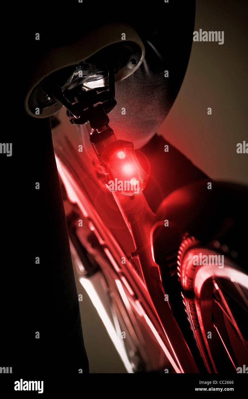 Rear view of a red back light on a bicycle being ridden at night by an ...