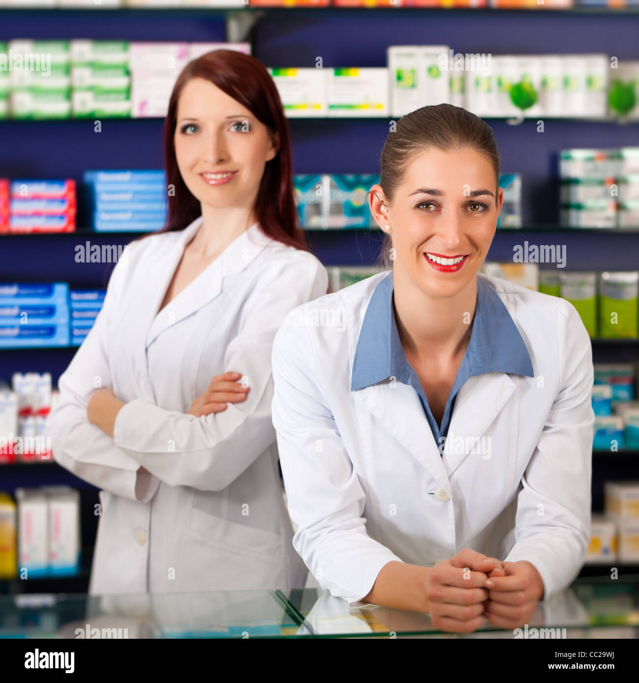 Two female pharmacists standing in pharmacy or drugstore in front of ...