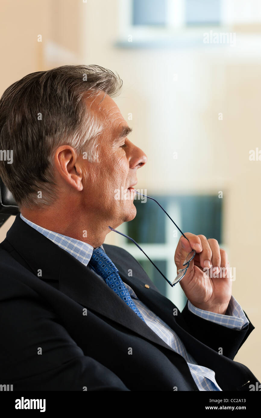 Business - mature boss contemplating in his office; he is looking out ...