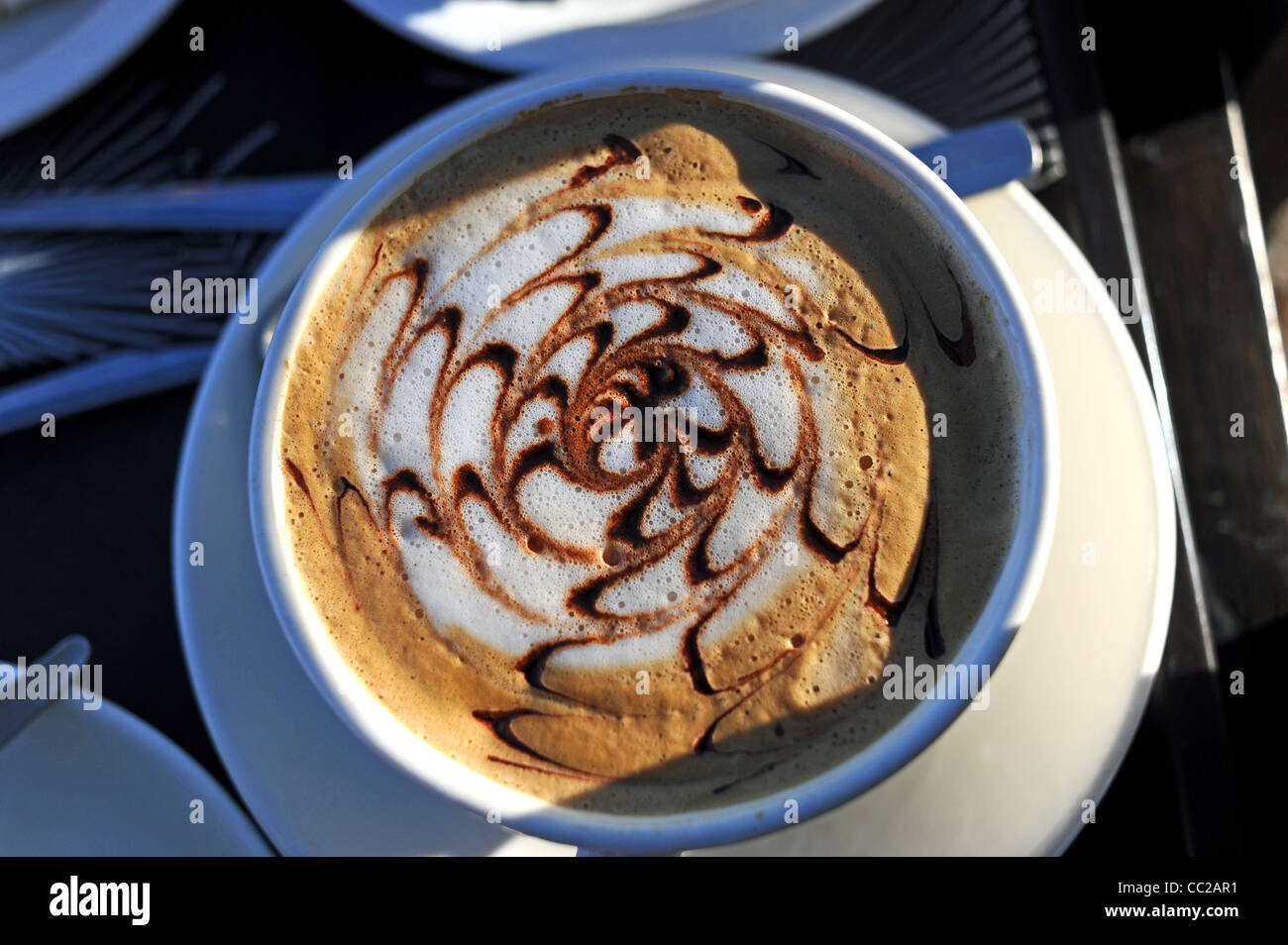 A cup of Cappuccino coffee with pattern drawn in froth and a slice of ...