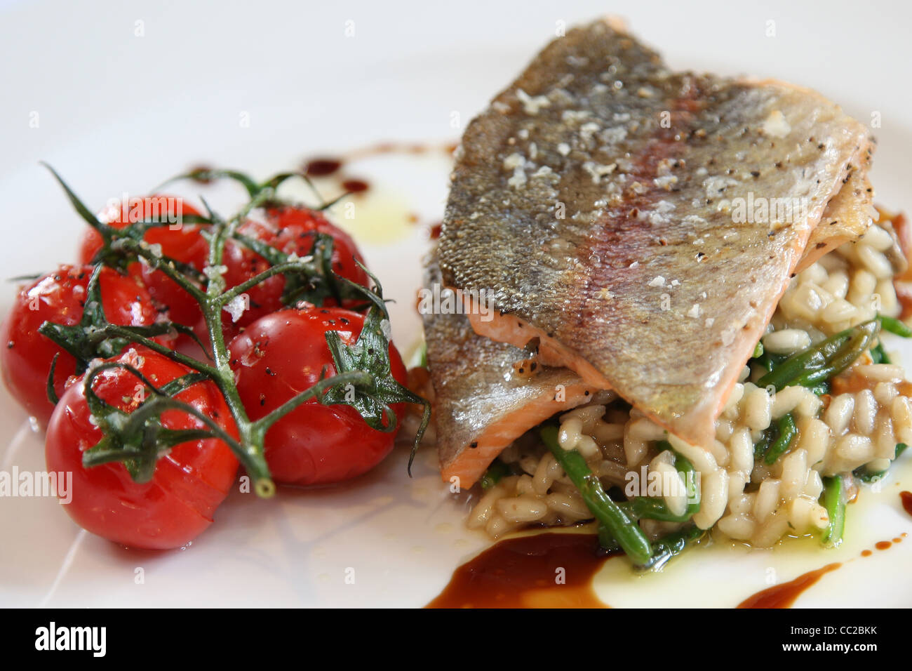 Fish On Risotto With Tomatoes And Sauce Stock Photo - Alamy