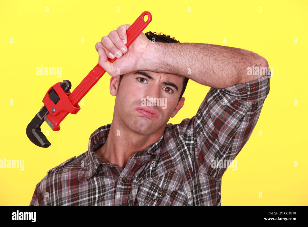 exhausted craftsman with adjustable spanner against yellow background ...