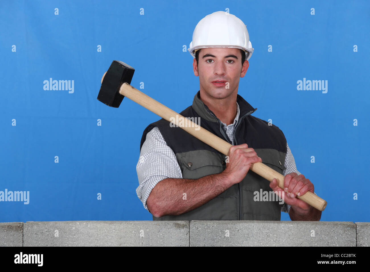 Man lifting hammer next to wall Stock Photo - Alamy