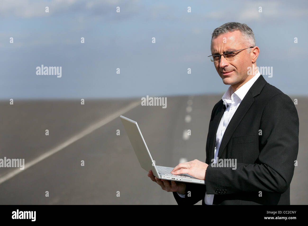 Man with laptop stood on road Stock Photo - Alamy