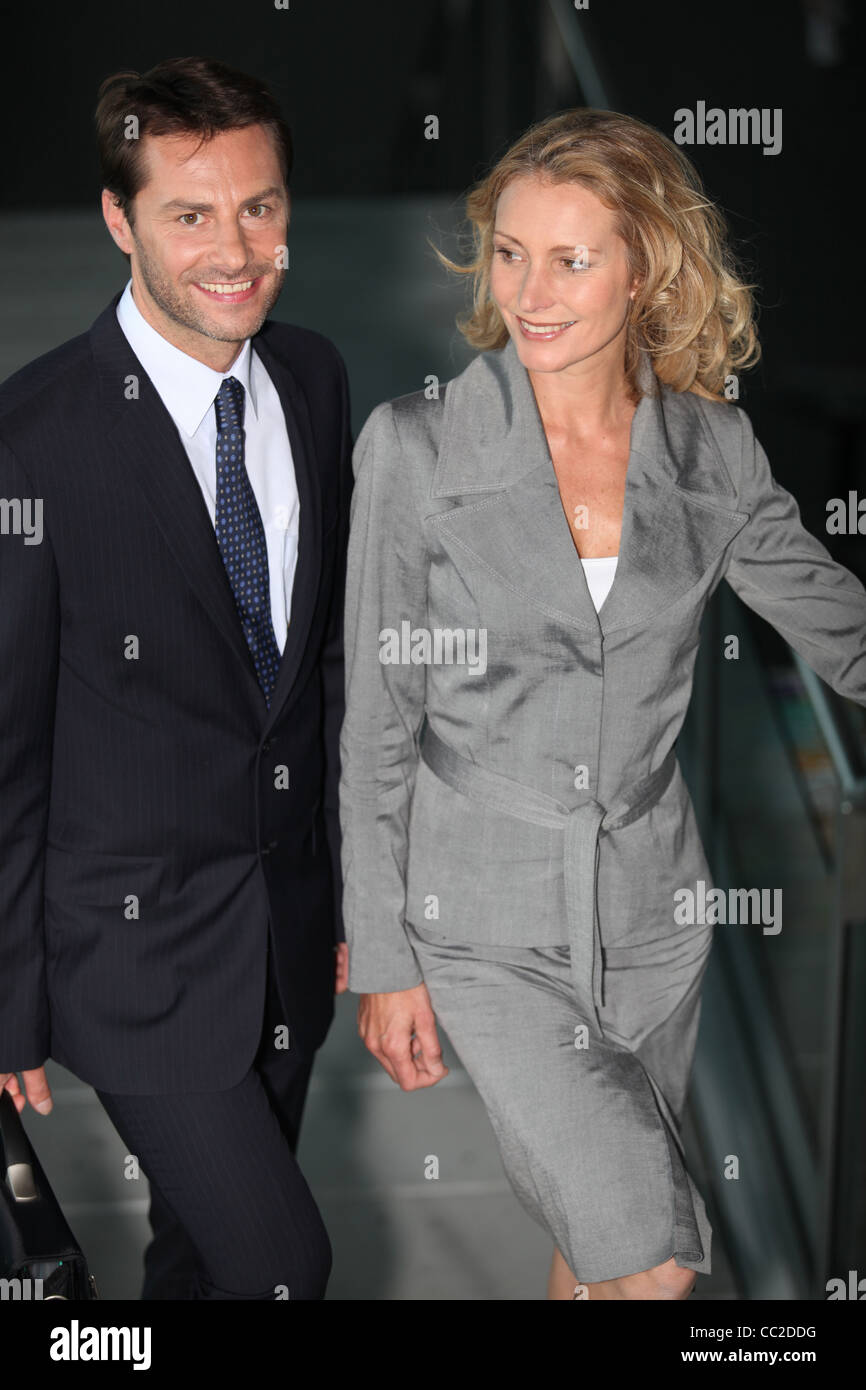Executive couple walking down a ramp Stock Photo - Alamy
