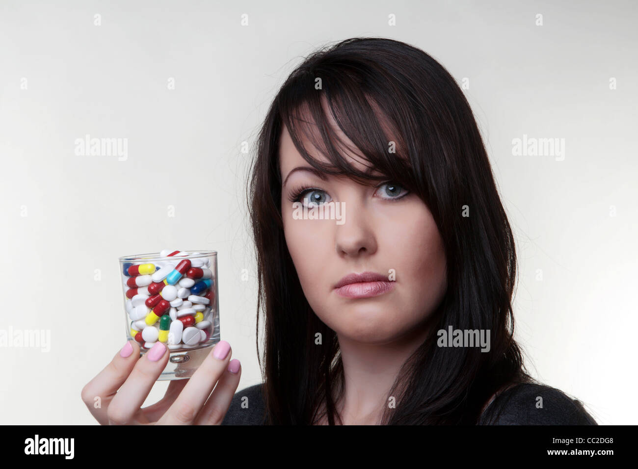 woman holding a small gall full of pill looking like she going to take ...