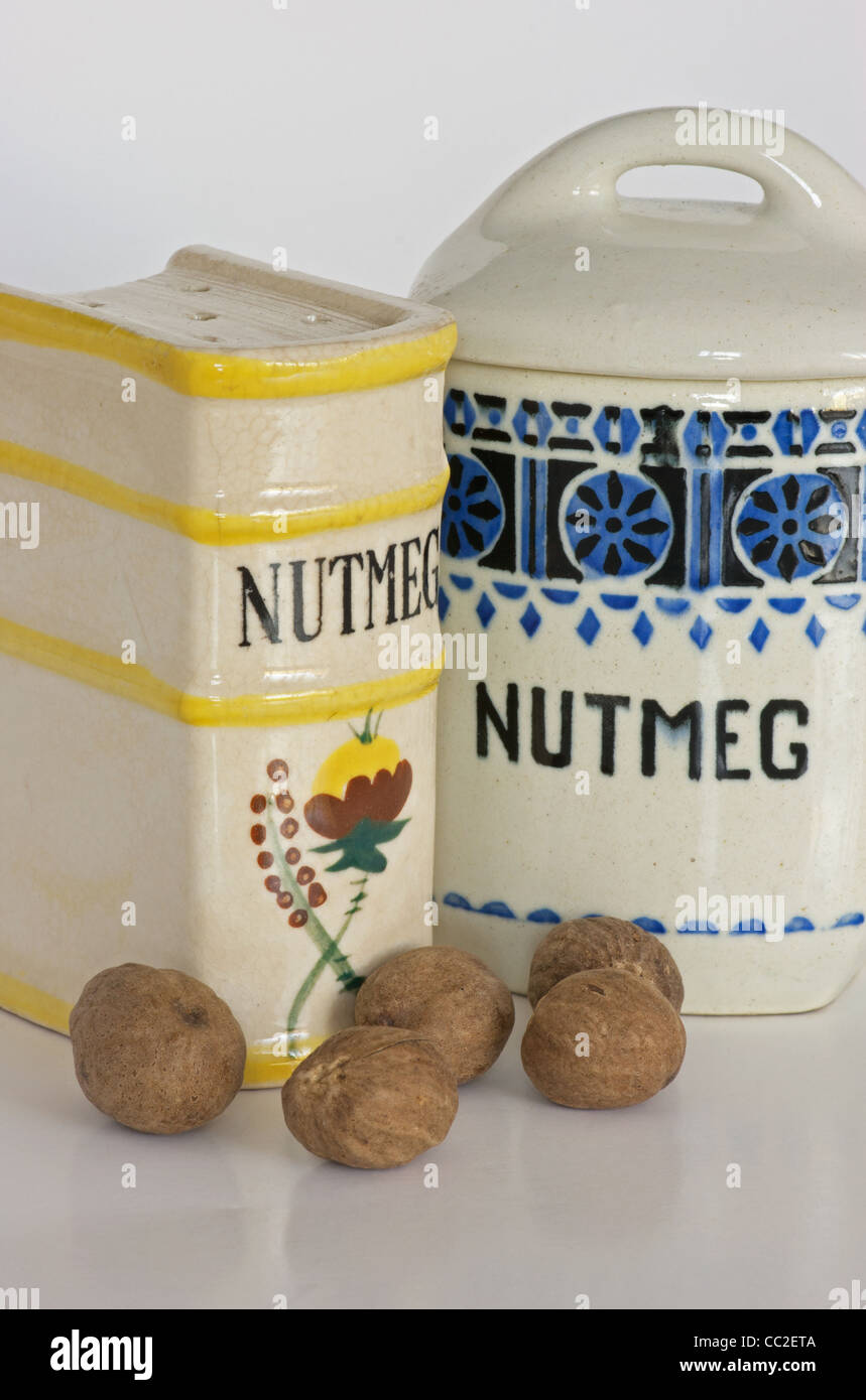 Whole nutmeg with two old ceramic nutmeg containers. One is a shaker ...