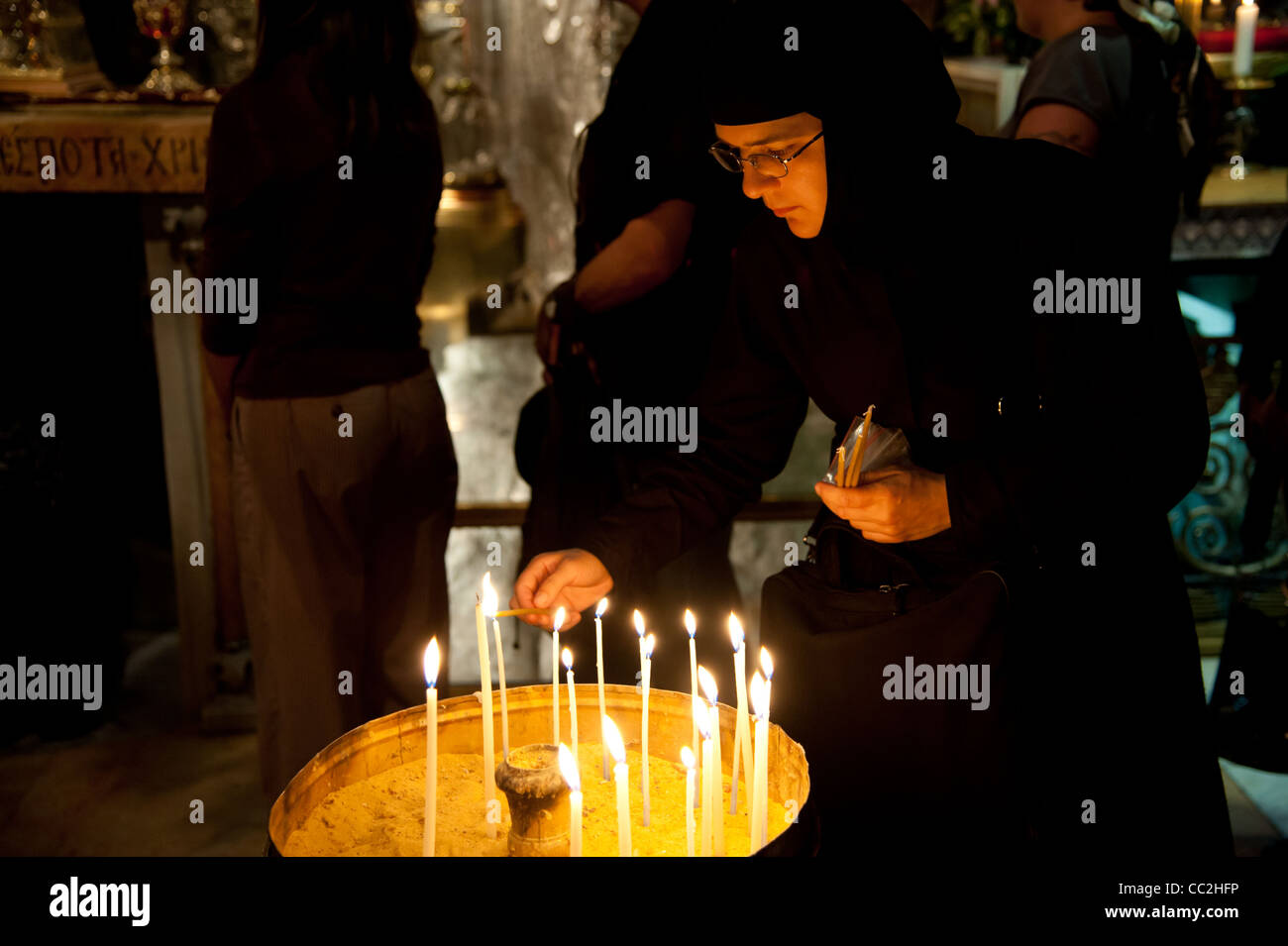 A nun lights candles in the Church of the Holy Sepulchre, traditional ...