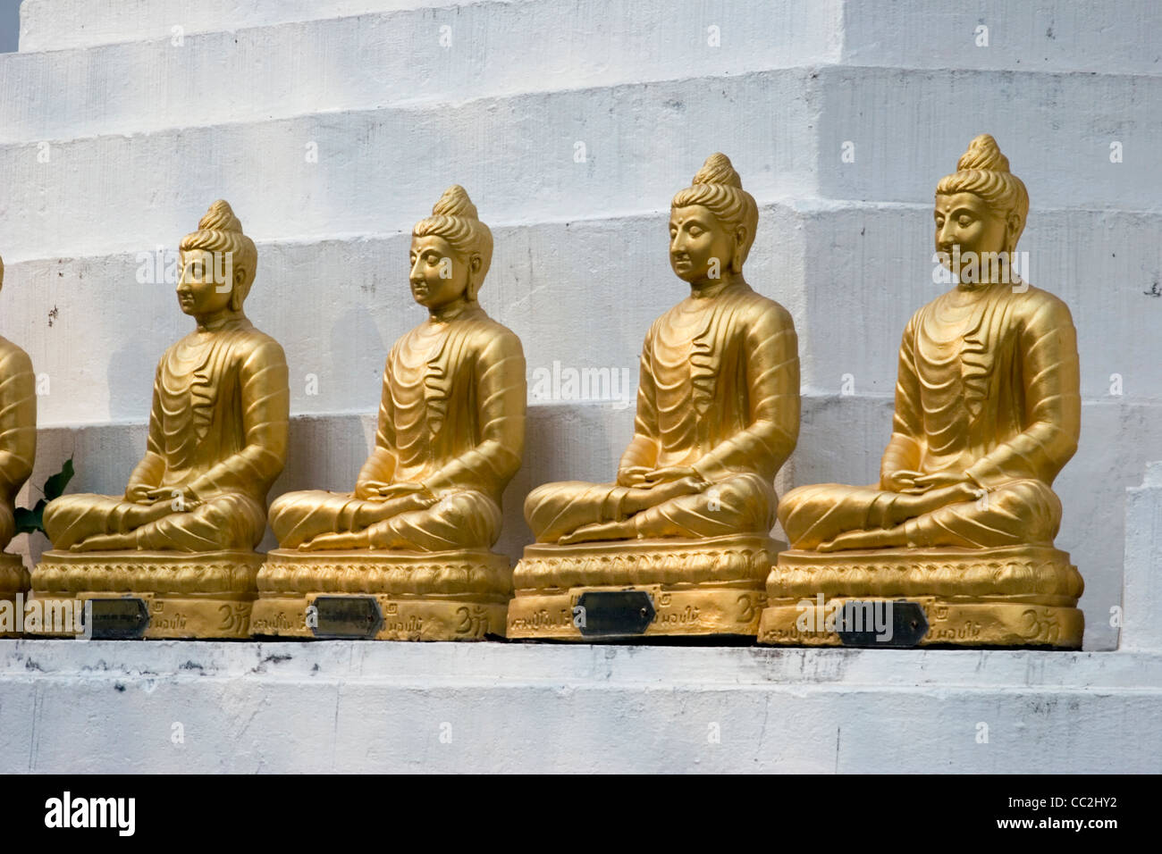 A row of gold Buddhist statues line a wall of an ancient and historic ...