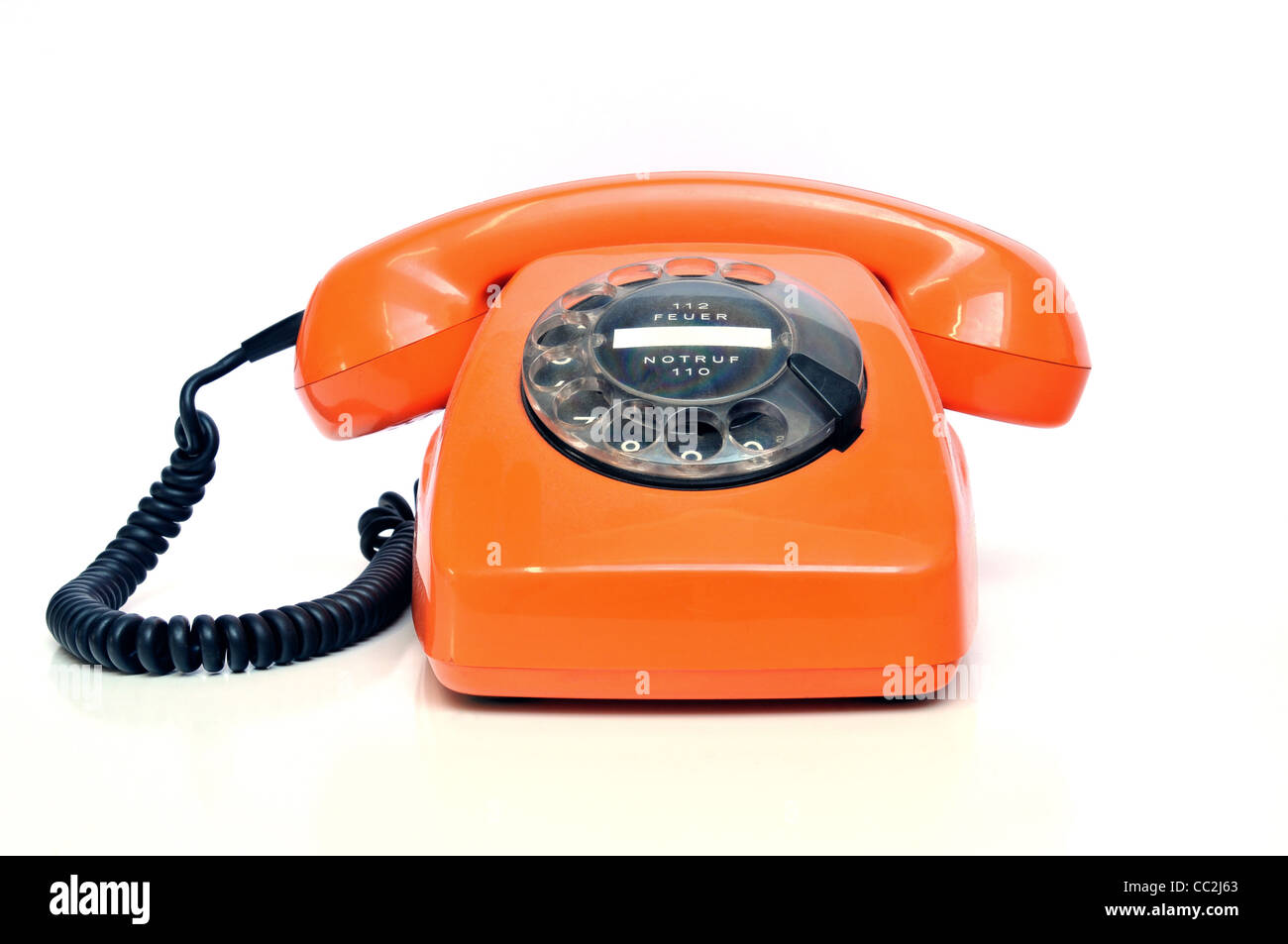 Old fashioned orange colored retro telephone over white background ...