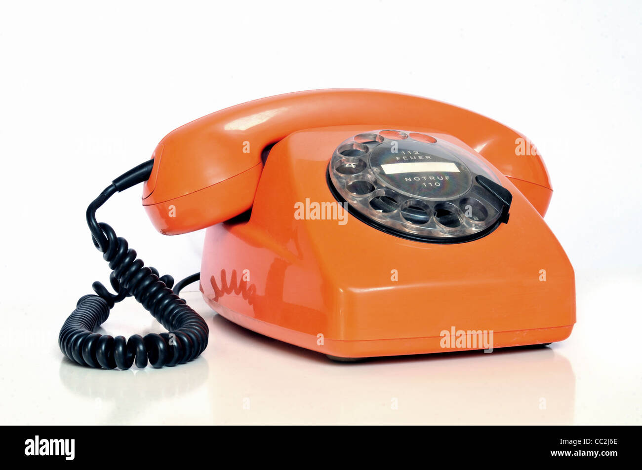 Old fashioned orange colored retro telephone over white background ...