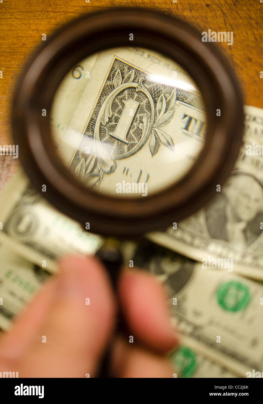 Hand holding magnifying glass over dollar bills, studio shot Stock ...