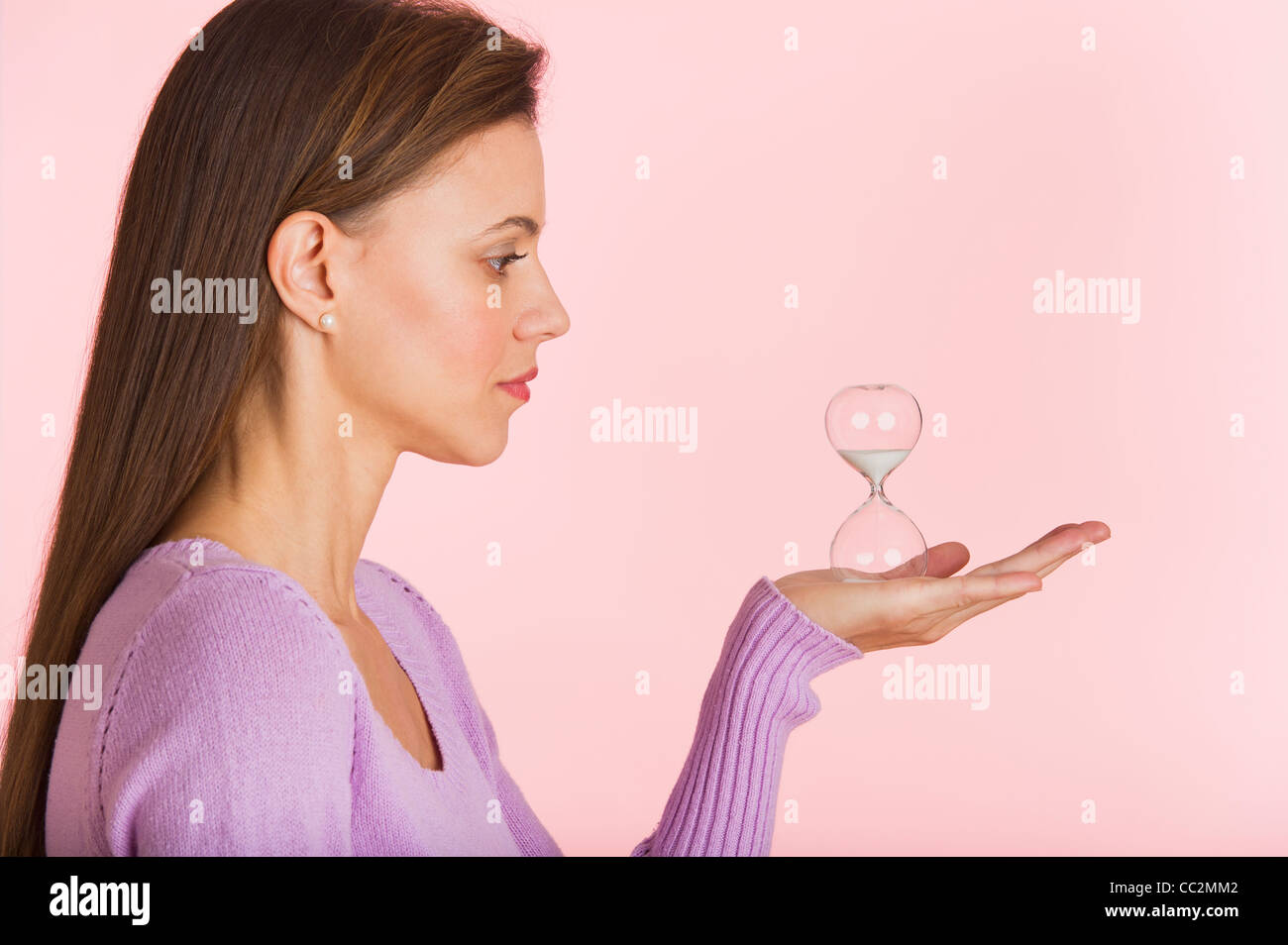 Studio shot of woman holding small hourglass Stock Photo - Alamy