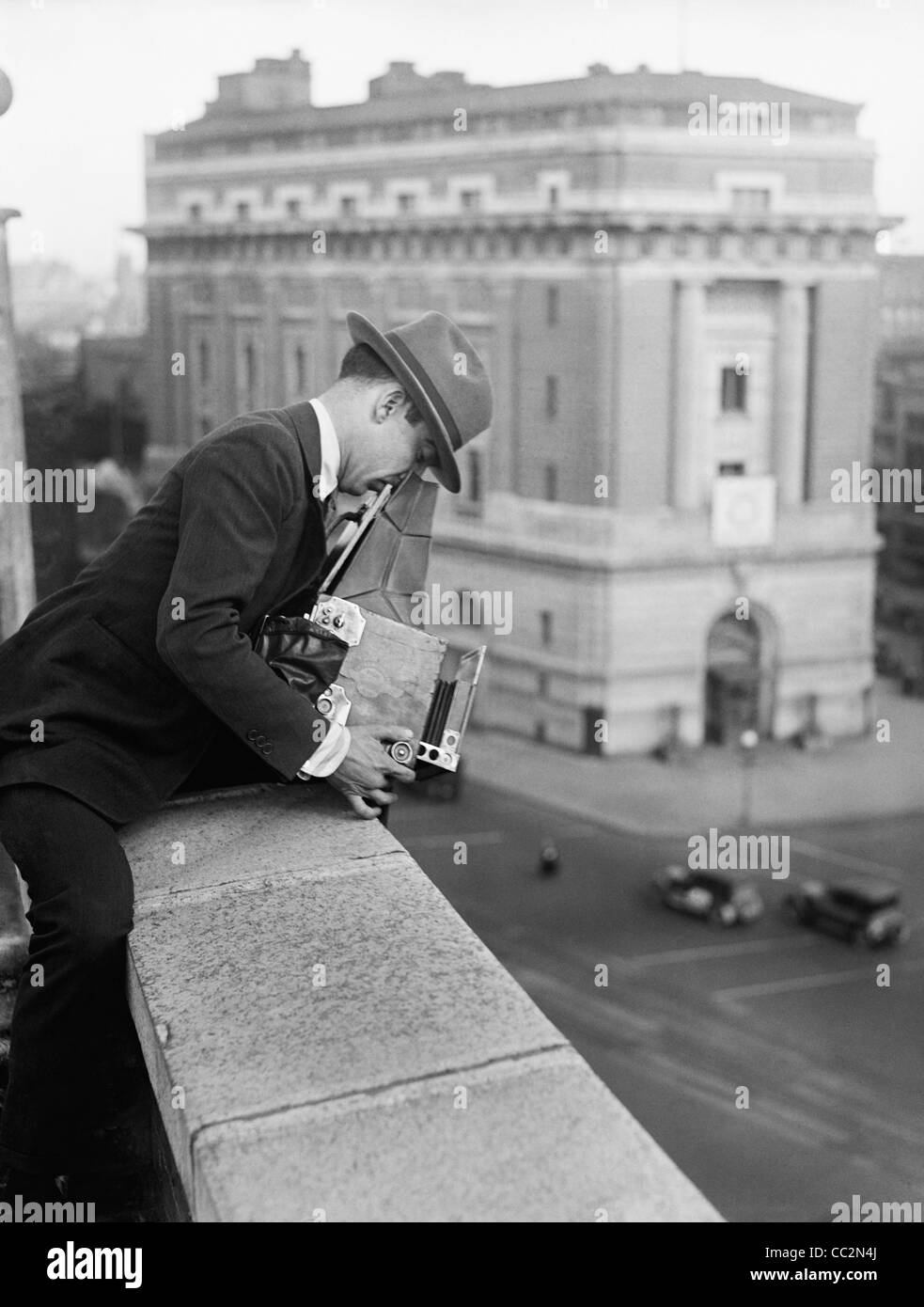 Photo circa 1910s of a photographer balanced precariously on a rooftop ...