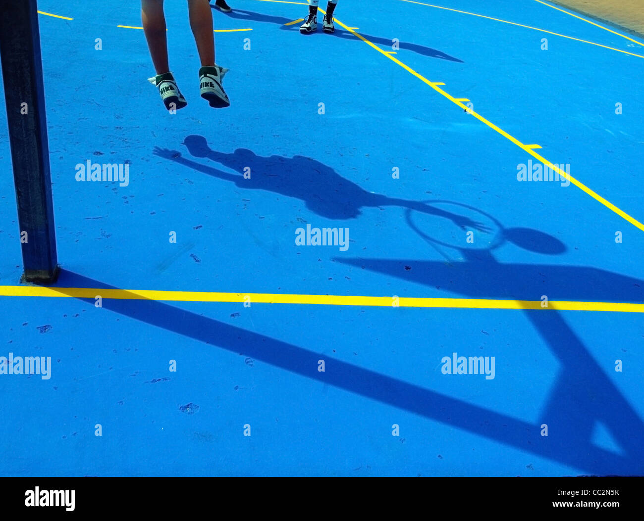 Young men play basketball, with strong shadows reflecting the action ...