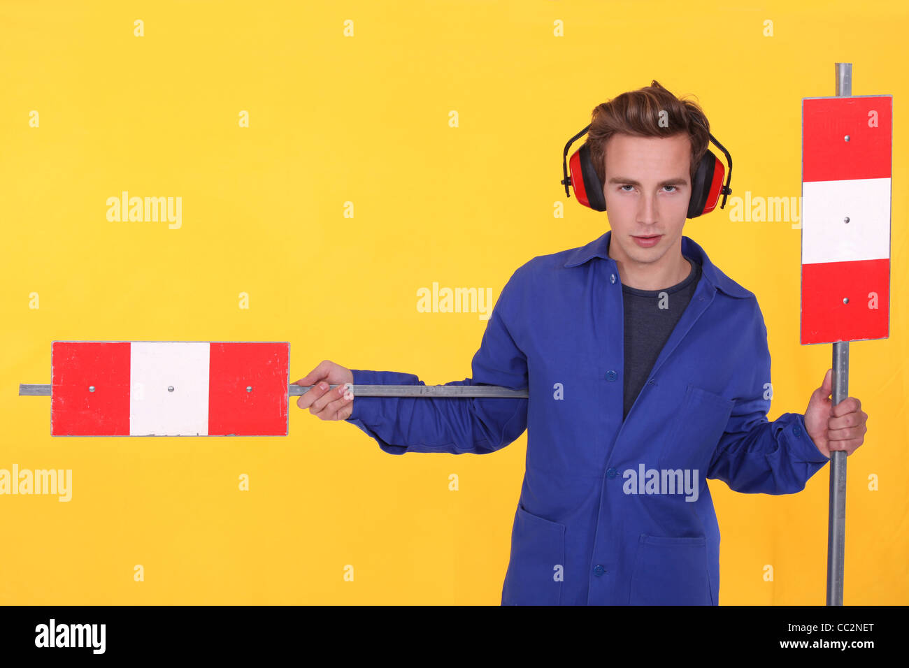 Man in ear defenders with warning signs Stock Photo - Alamy